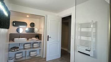 Um corredor com uma porta branca, um radiador e um pequeno vaso com planta.