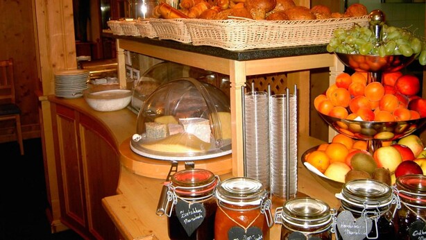 Uma mesa de buffet com pão, doces e uma cesta de frutas.