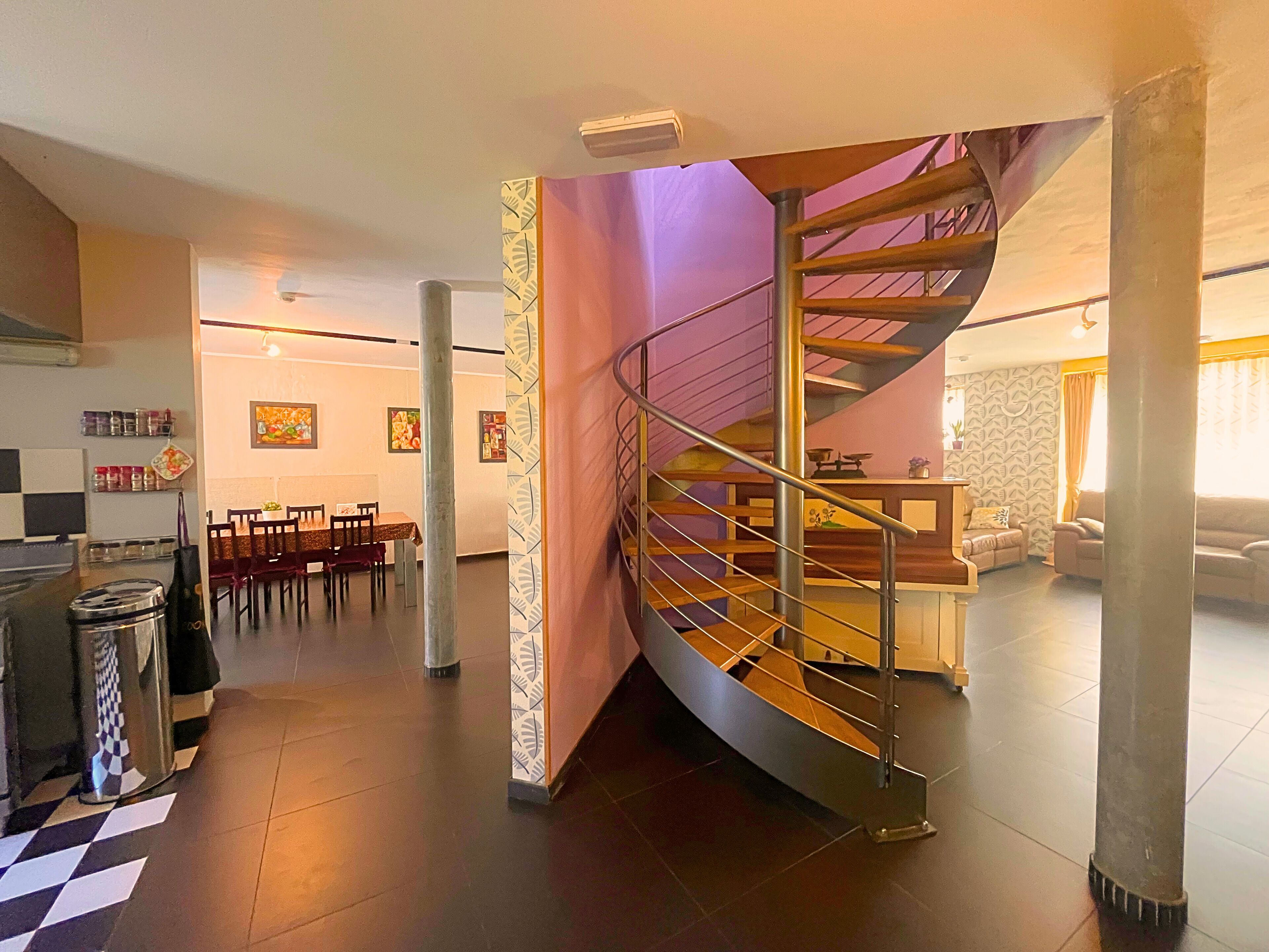 Um interior moderno com uma escadaria em espiral, uma área de jantar e uma sala de estar.