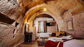 Quarto com paredes de pedra, uma cama, um radiador e uma televisão.