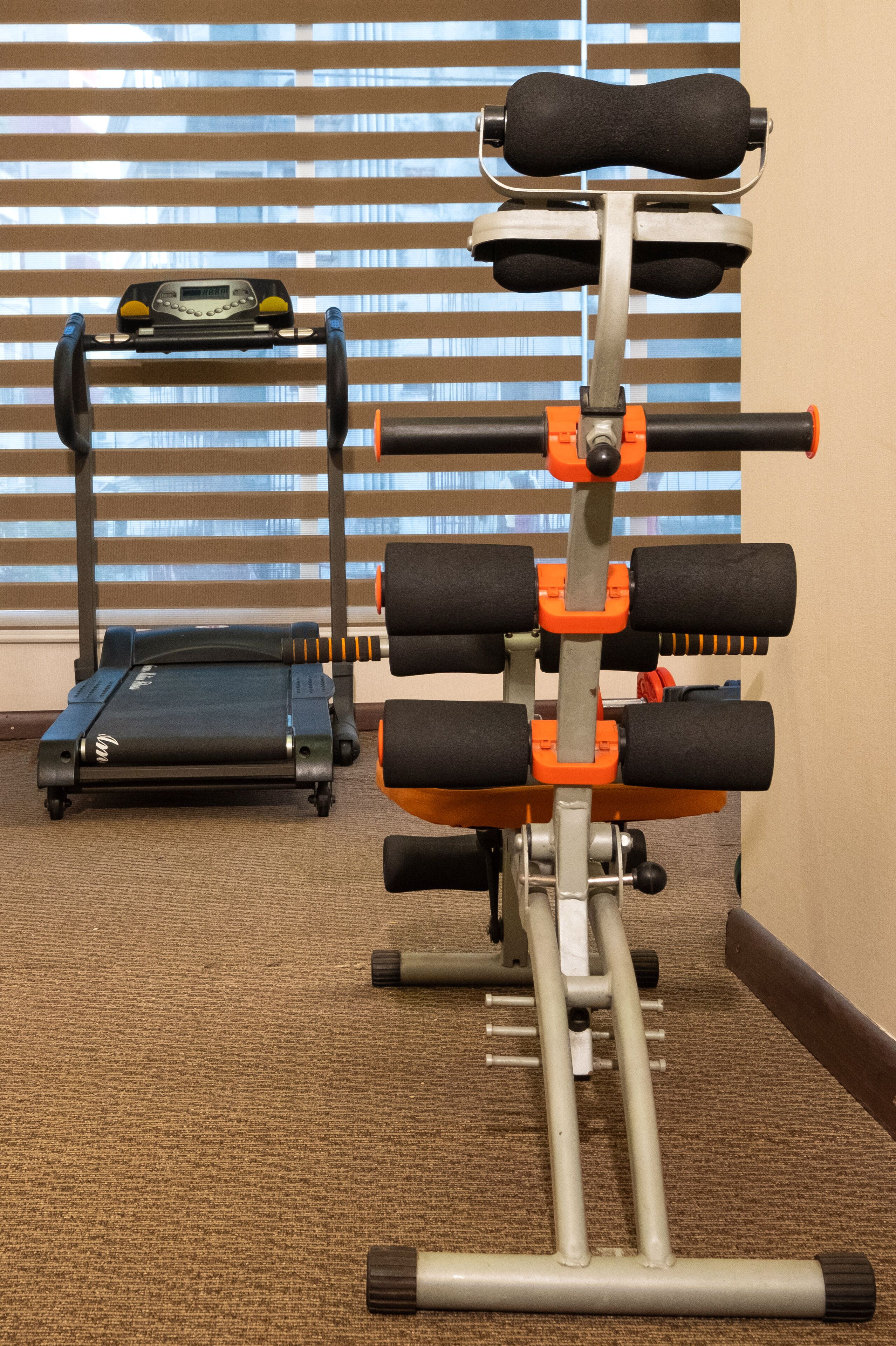 Academia com equipamentos de exercícios, incluindo esteira e aparelho multifuncional de musculação.