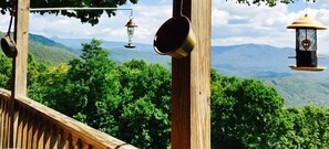 Um deque de madeira com lanternas penduradas e vista para uma paisagem montanhosa.
