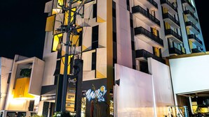 Um hotel com vários andares e design moderno, com varandas e uma entrada destacada com sinalização.
