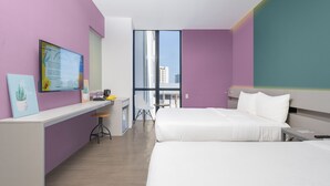 Quarto de hotel moderno com uma janela grande, uma escrivaninha com cadeira e duas camas.