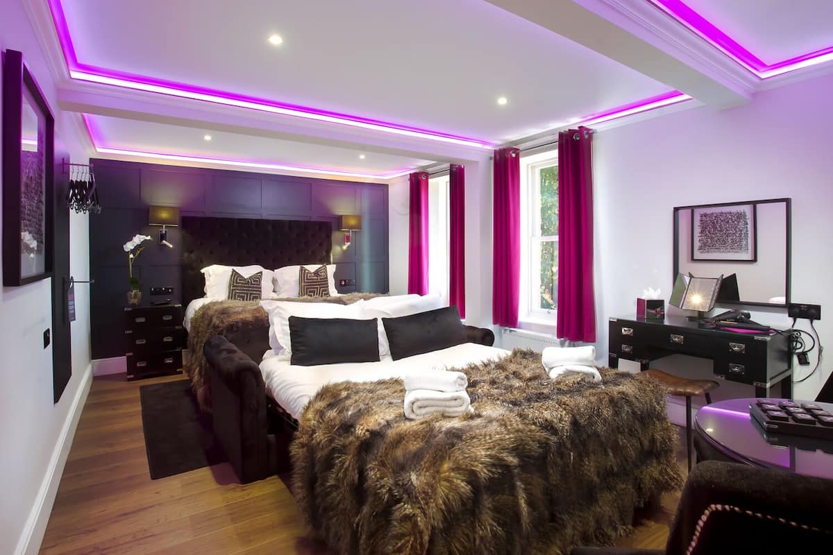 Quarto moderno com uma cama grande, uma escrivaninha e um computador.