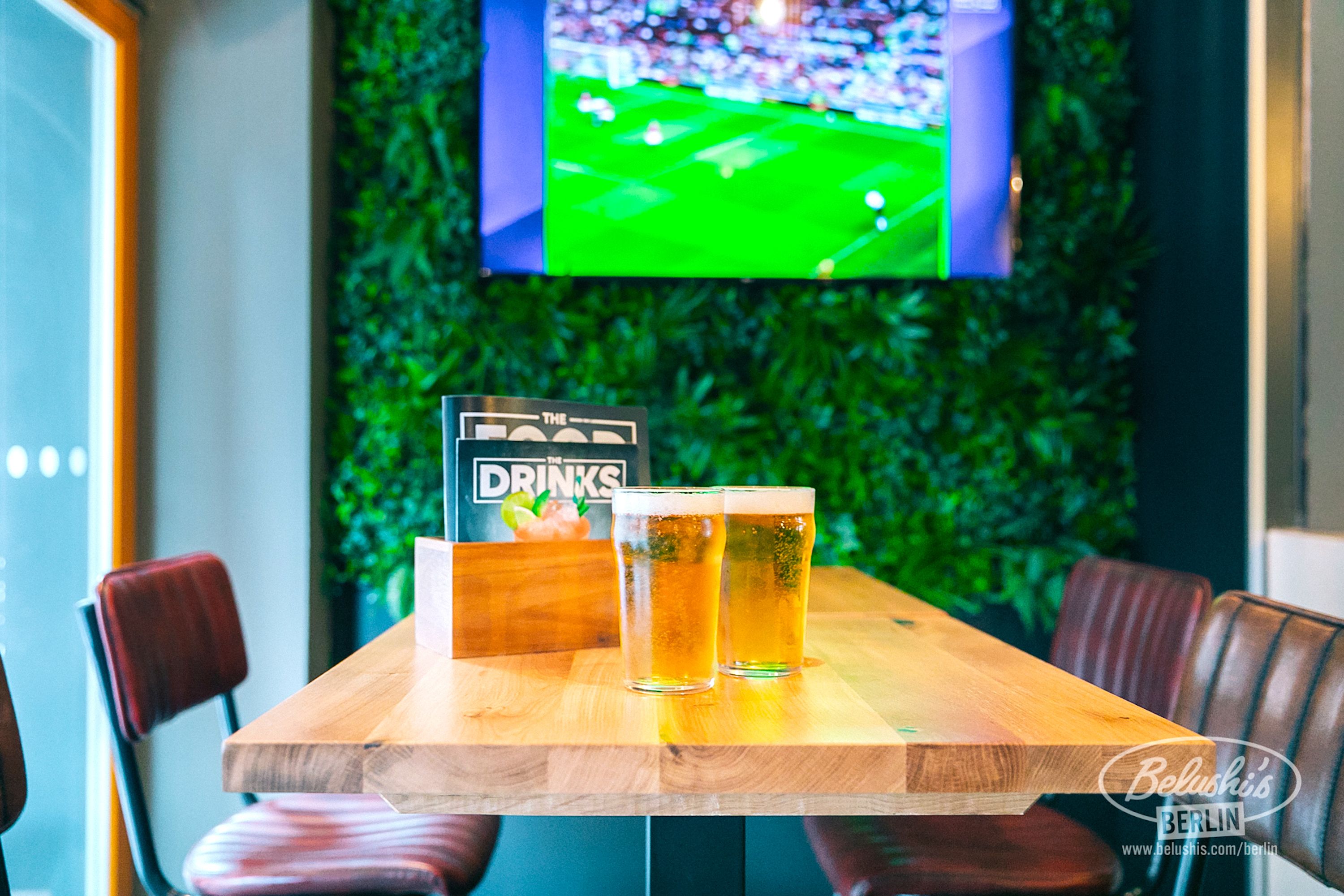 Uma mesa de madeira com duas cervejas e um cardápio.