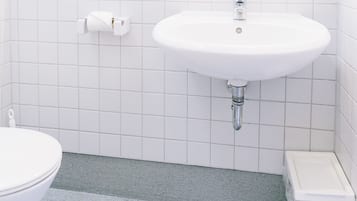 Casa de banho com lavatório branco, sanita e parede revestida a mosaicos azuis.