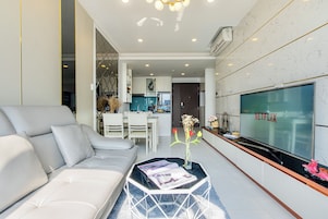 Uma sala de estar moderna com sofá, mesa de centro e uma TV exibindo 'NETFLIX'.