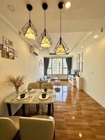 Uma sala de jantar moderna com mesa de vidro, cadeiras e luminárias pendentes.