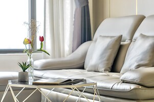 Uma sala de estar moderna com um sofá de couro, uma mesa de centro de vidro e um vaso com flores.