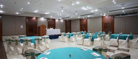Uma sala de conferências com mesas redondas, cadeiras e um púlpito.