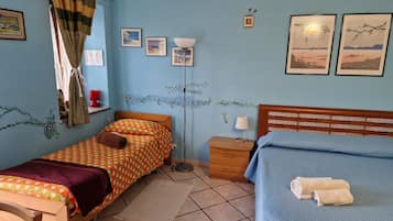 Quarto com duas camas, mesa de cabeceira de madeira, luminária de chão e decorações nas paredes.