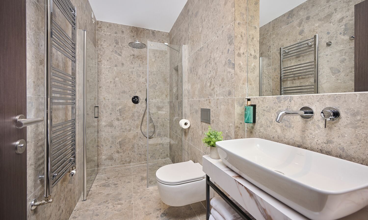 Uma casa de banho moderna com chuveiro, sanita e lavatório.
