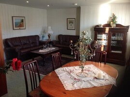 Uma sala de estar aconchegante com uma mesa de jantar de madeira, um sofá de couro marrom e uma estante de livros.