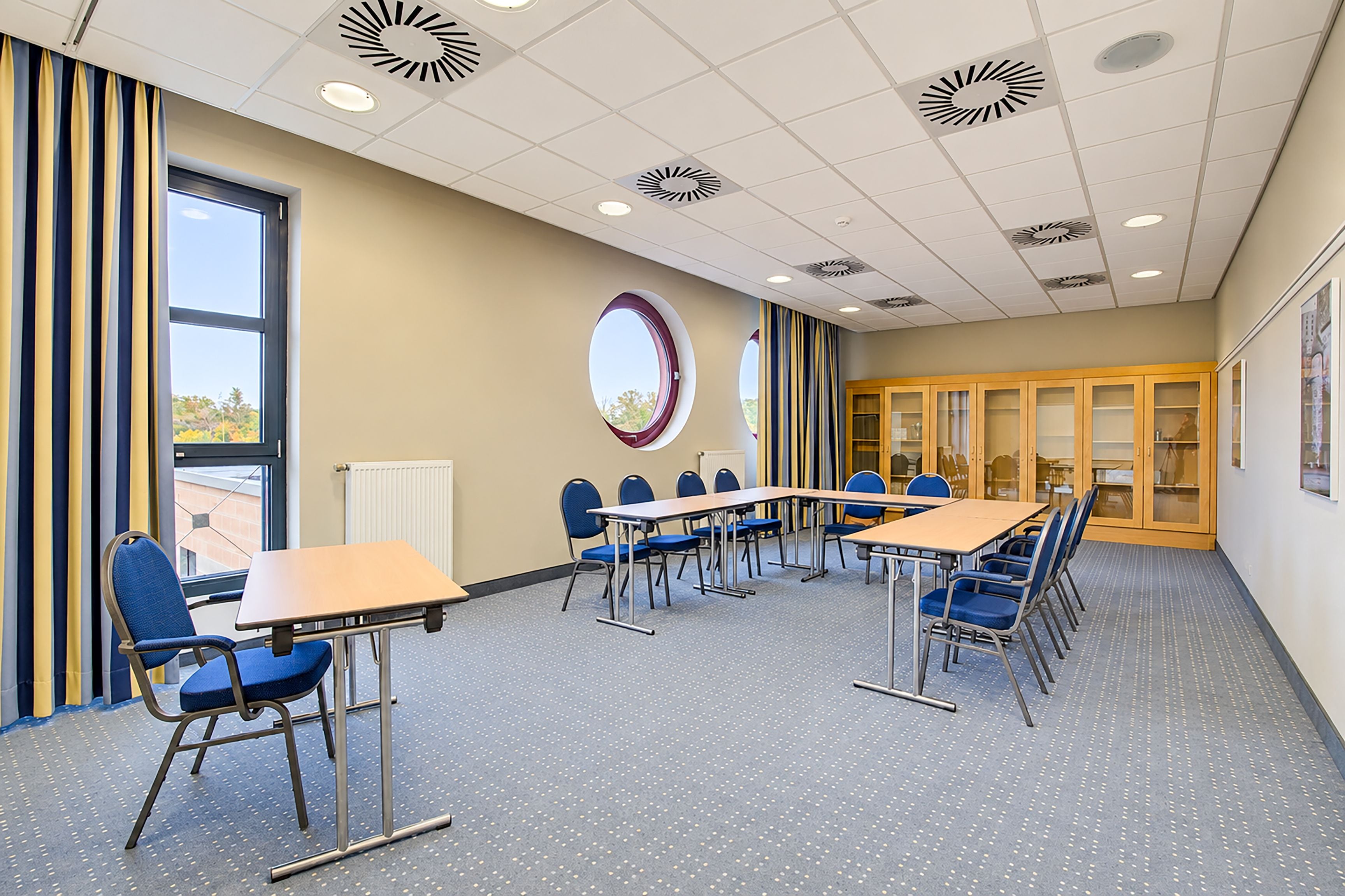 Uma sala de conferências com uma mesa comprida, cadeiras, uma janela grande e um claraboia circular.