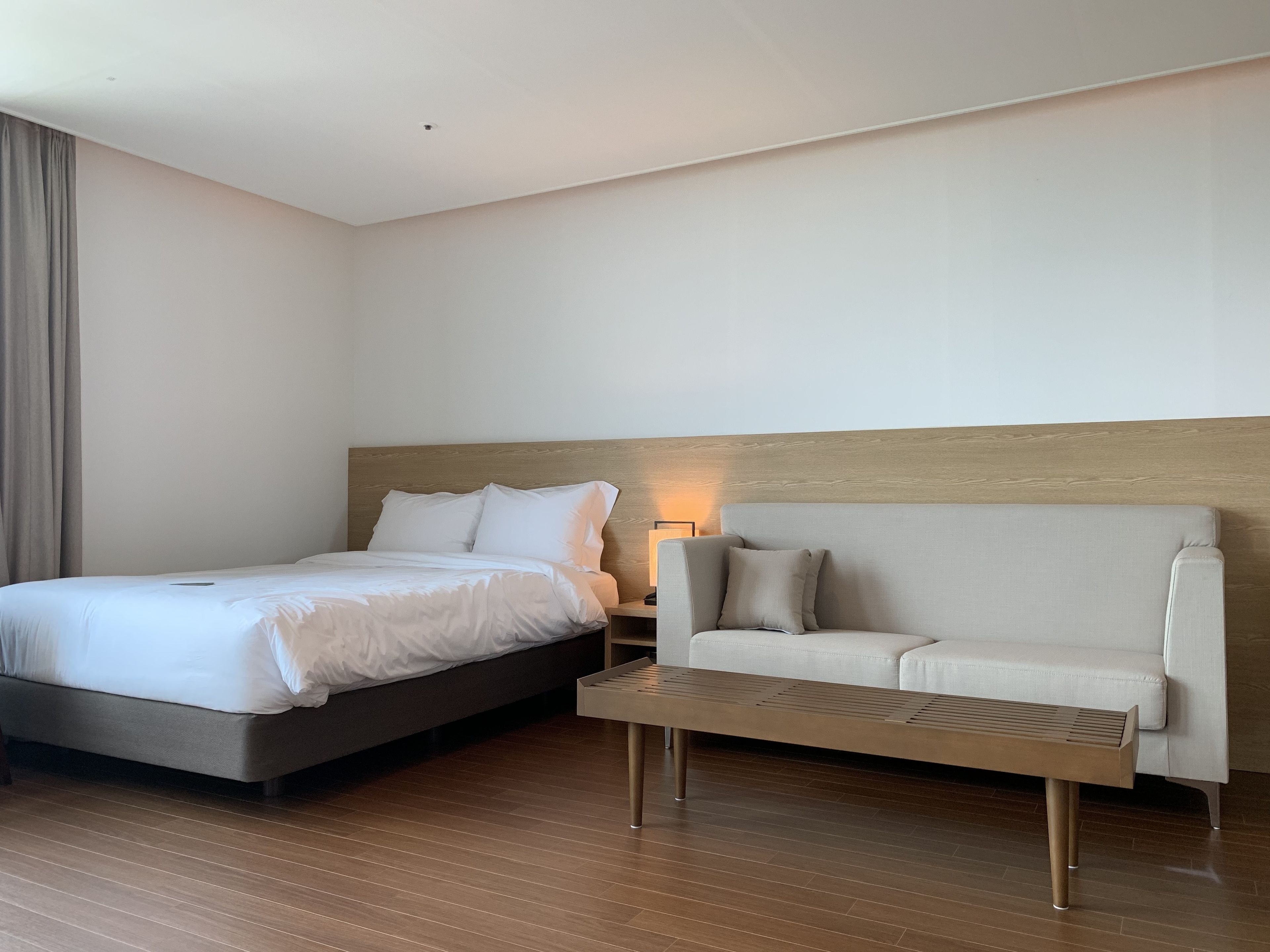 Quarto de hotel com uma cama, um sofá, uma mesa de cabeceira e uma luminária.