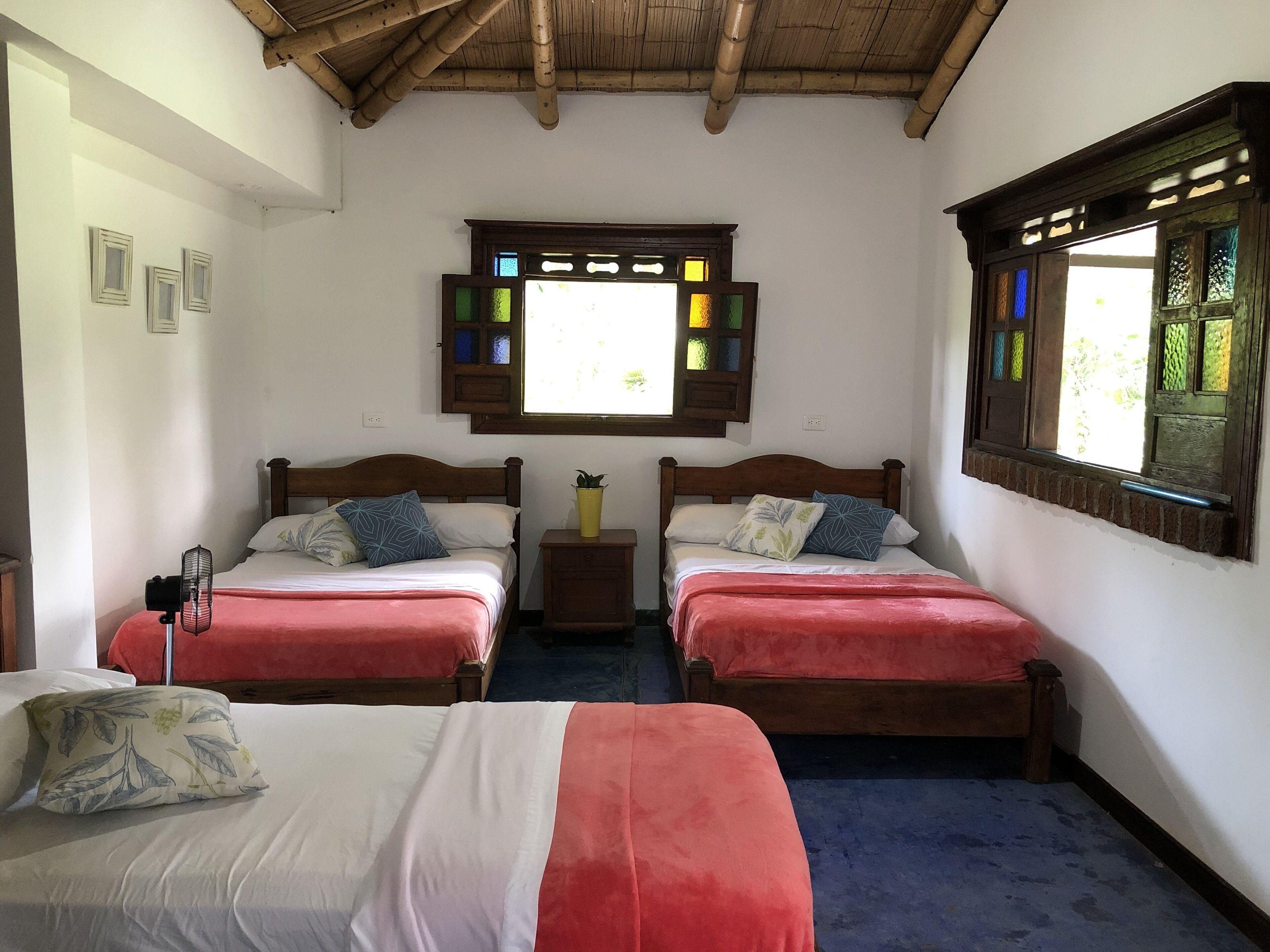 Quarto com duas camas, uma mesa pequena e janela com vitrais.