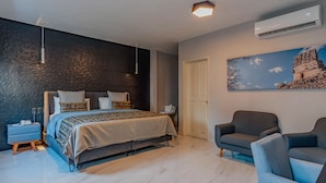 Quarto moderno com cama, dois mesinhas de cabeceira, uma cadeira e um quadro na parede.