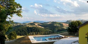 Área de piscina com vista para colinas ondulantes e uma cordilheira distante.
