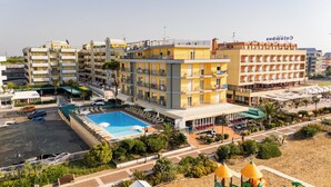 Um hotel com vários andares, piscina e áreas de estar ao ar livre.