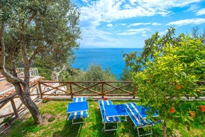 Terraço com cadeiras de descanso listradas em azul com vista para o mar.