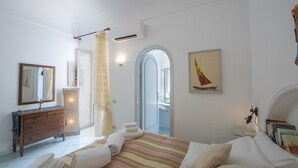 Um quarto com uma cama, penteadeira, espelho e uma pintura.