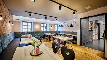 Um restaurante moderno com piso de madeira, cadeiras pretas e mesas decoradas com flores.