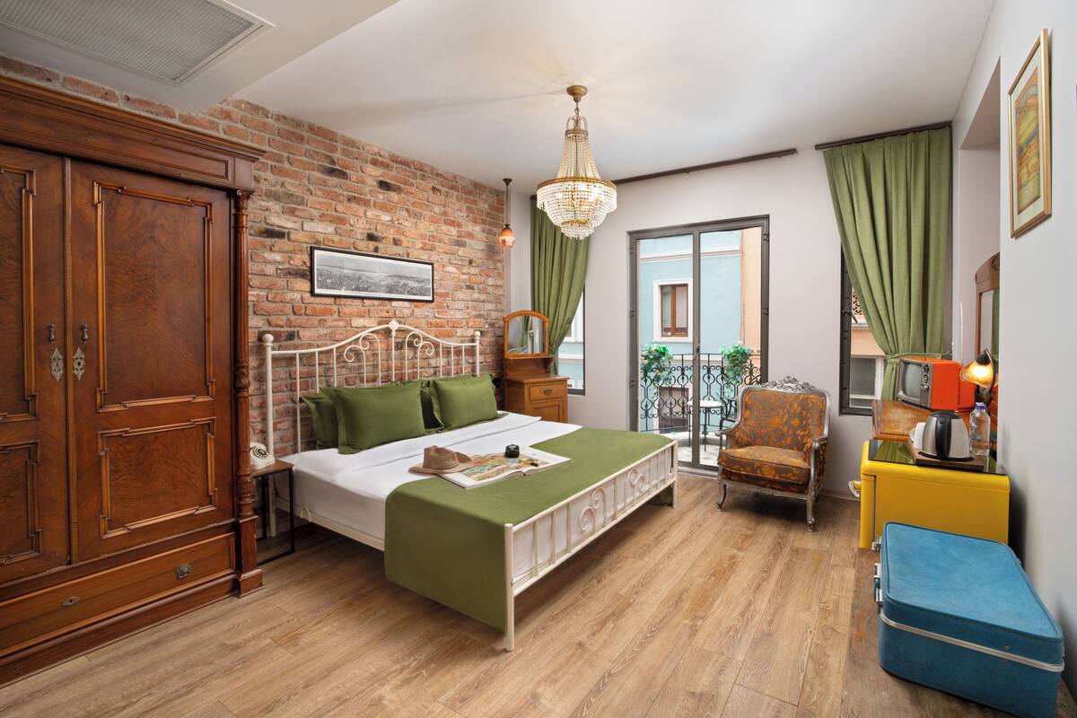 Um quarto com cama, cômoda, cadeira, mesa com abajur e mala.