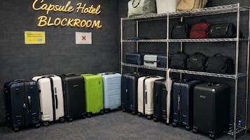 Quarto compacto em hotel cápsula, com malas organizadas no chão e prateleiras.