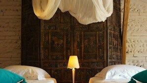 Quarto com duas camas, piso de madeira e painéis entalhados na parede.