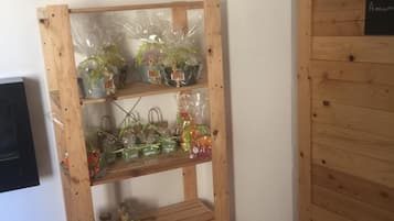 Uma estante de madeira com várias prateleiras, algumas contendo plantas em vasos e outras com potes.