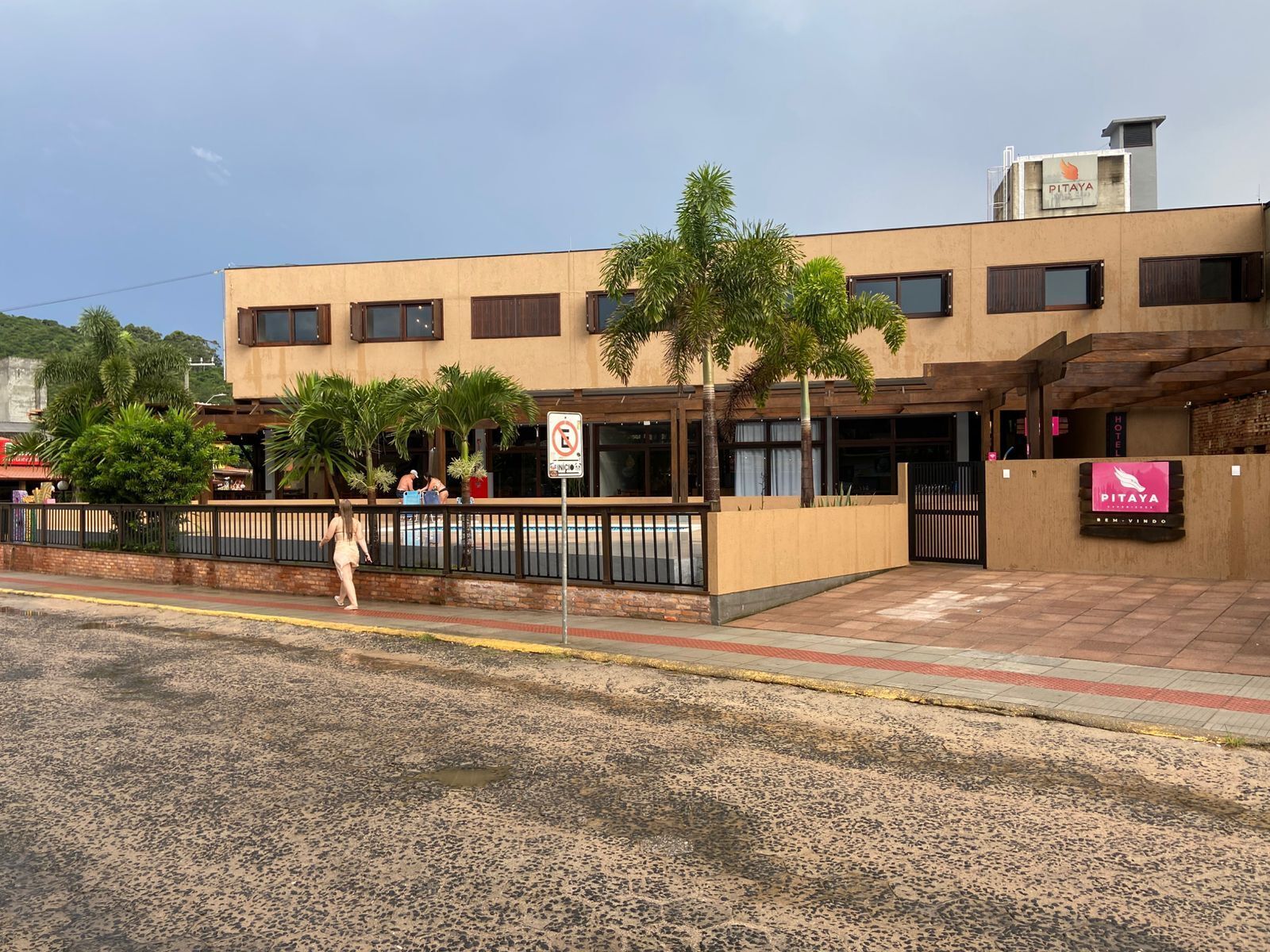 Um hotel com fachada plana, várias janelas e uma placa indicando área sem estacionamento.