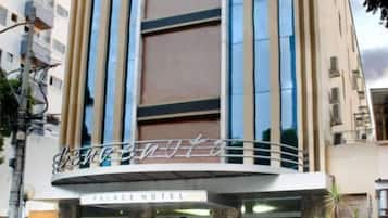 Um hotel com fachada moderna, exibindo um logotipo em destaque e o nome 'Palace Hotel' na entrada.
