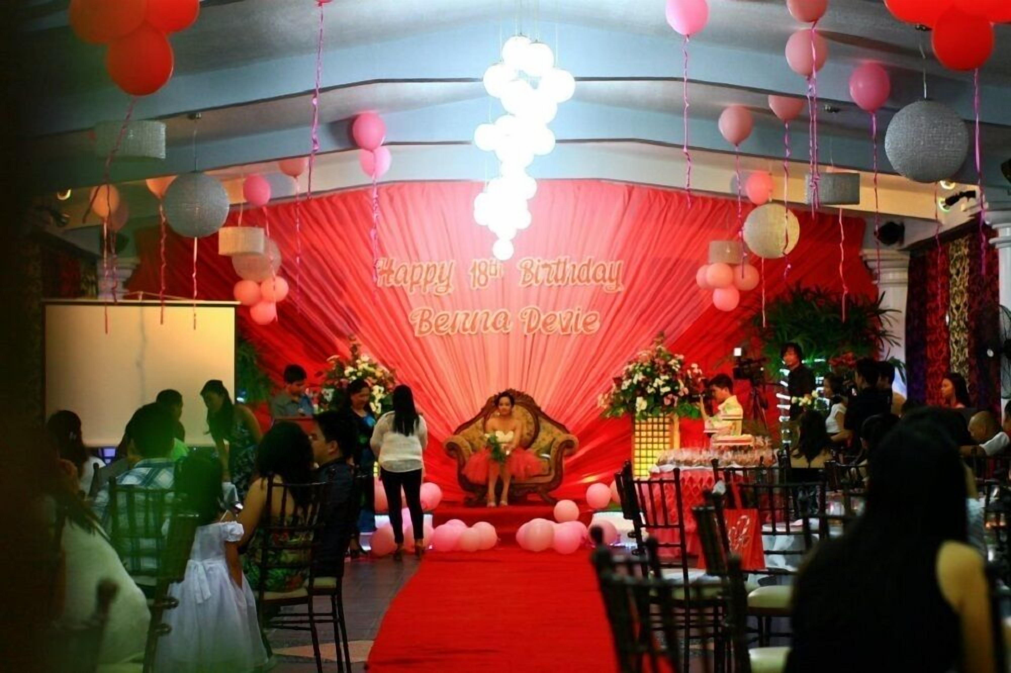 Um espaço decorado para eventos, com tapete vermelho e palco para uma celebração de aniversário.