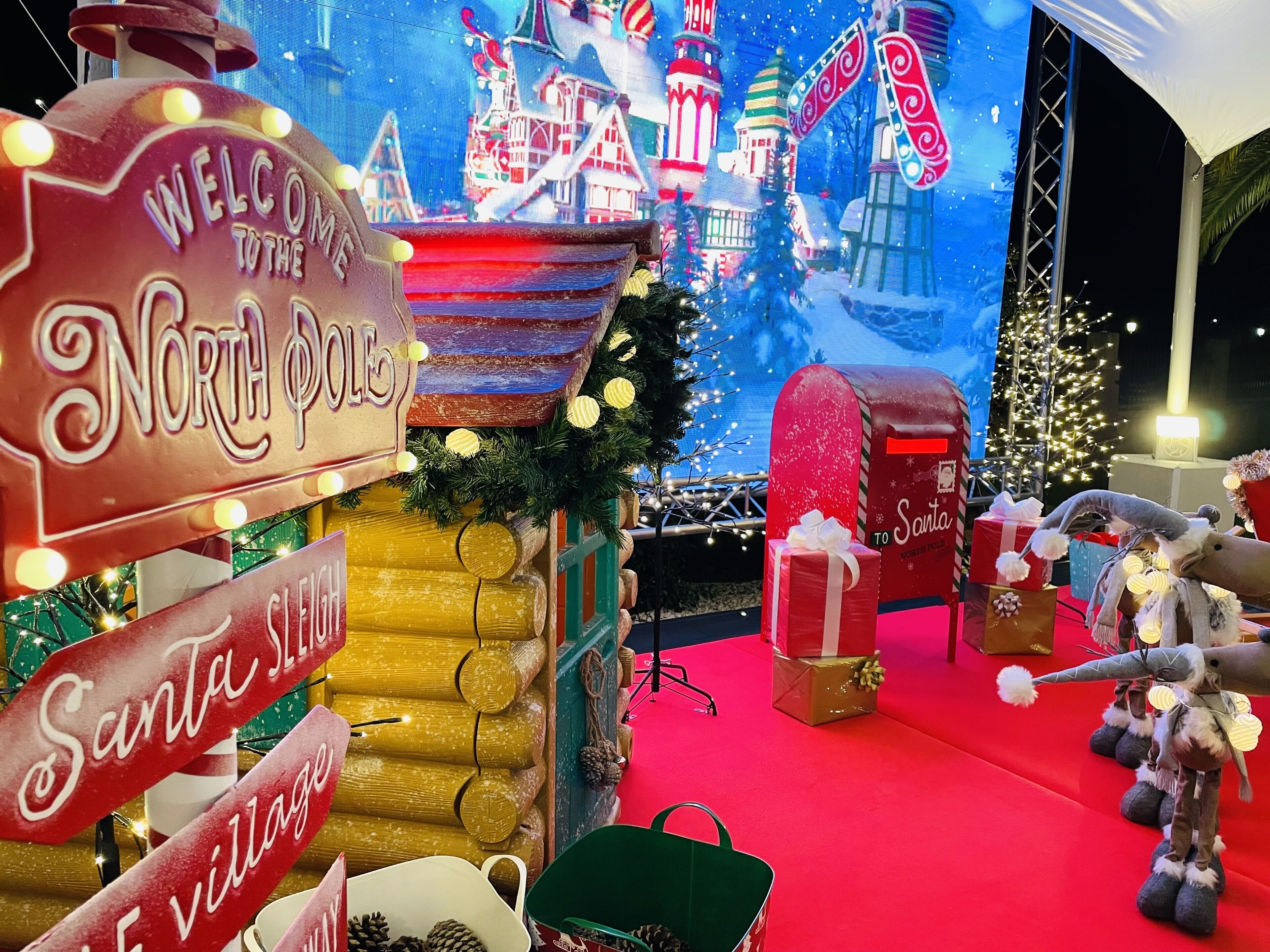 Decoração festiva com um letreiro 'Bem-vindos ao Polo Norte', uma caixa de correio do Papai Noel e uma figura de rena.