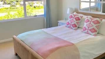 Quarto com uma cama grande, duas mesas de cabeceira e vista para o verde lá fora.