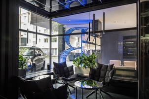 Um interior moderno com uma grande janela, cadeiras pretas, uma mesa de vidro e um vaso com planta.