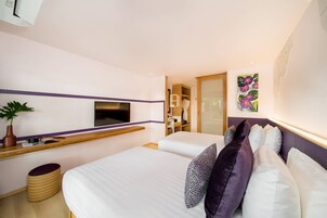 Quarto de hotel moderno com uma cama grande, televisão de tela plana na parede, mesa de cabeceira de madeira com uma planta e uma obra de arte colorida na parede.
