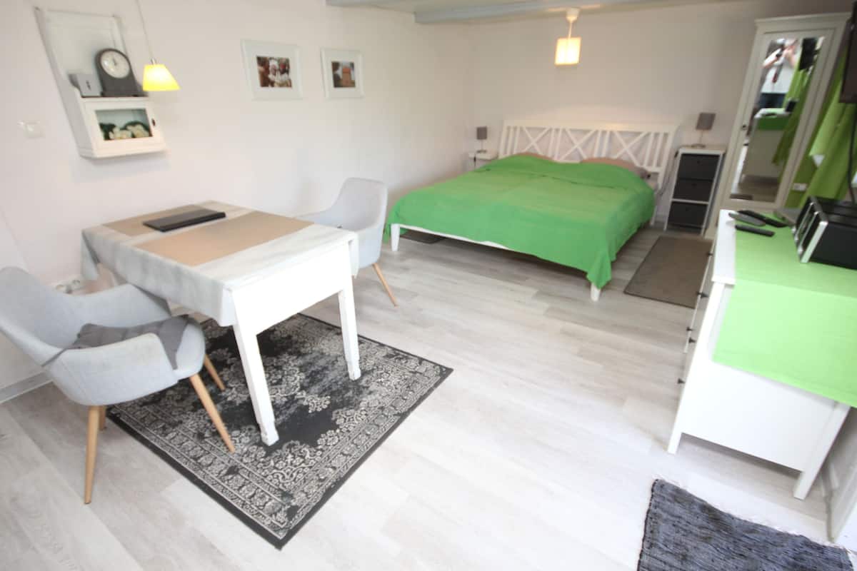 Quarto com cama, escrivaninha e cadeiras.