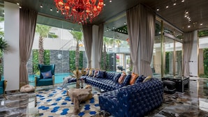 Uma sala de estar luxuosa com um sofá azul, uma mesa de centro de vidro e um candelabro vermelho.