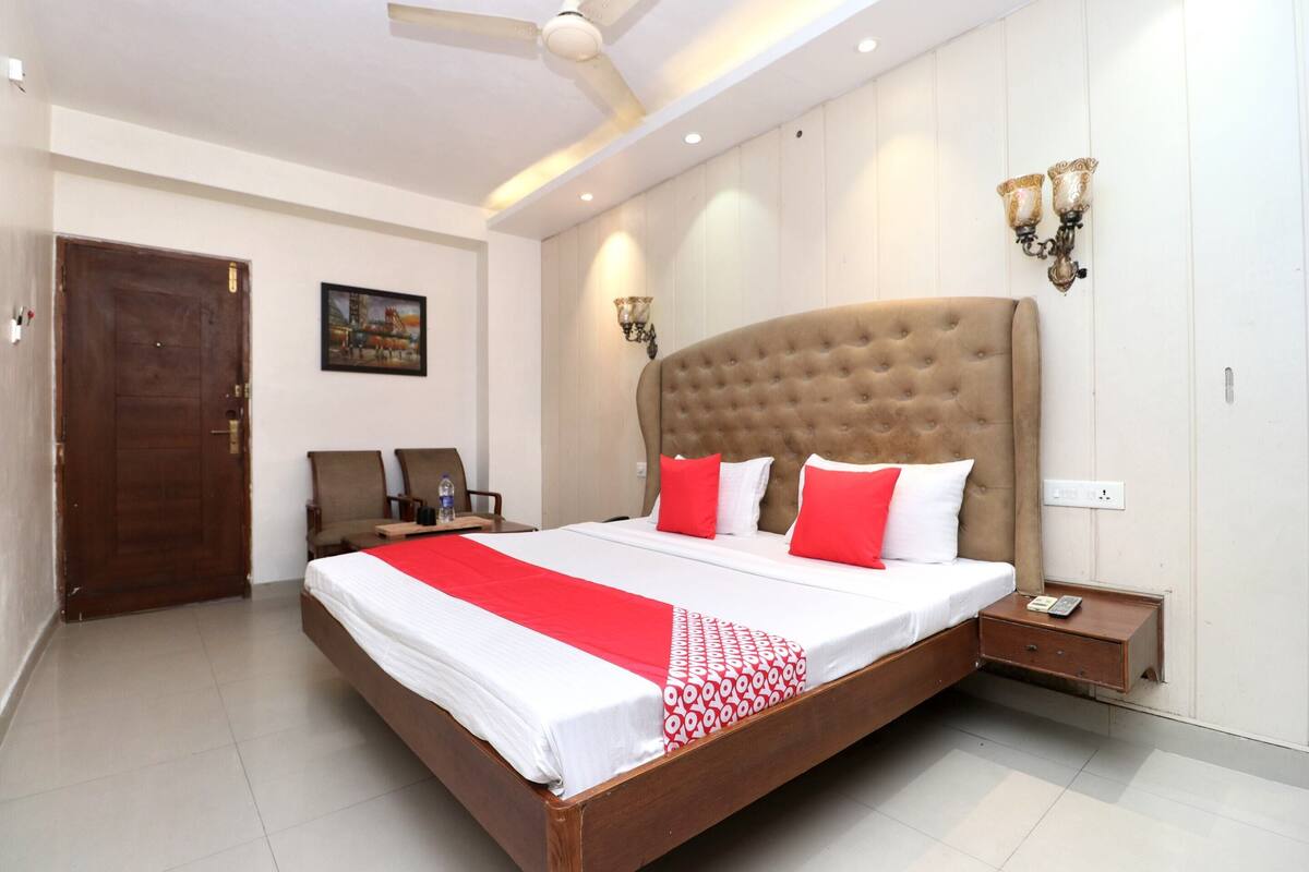 Quarto de hotel bem arrumado com uma cama grande, uma mesa de cabeceira de madeira, uma escrivaninha e uma cadeira.