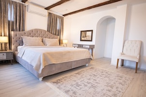 Quarto com uma cama grande, mesa de cabeceira, cadeira e espelho na parede.