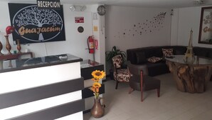 Uma área de recepção com balcão, relógio e aviso com informações de contato de emergência.