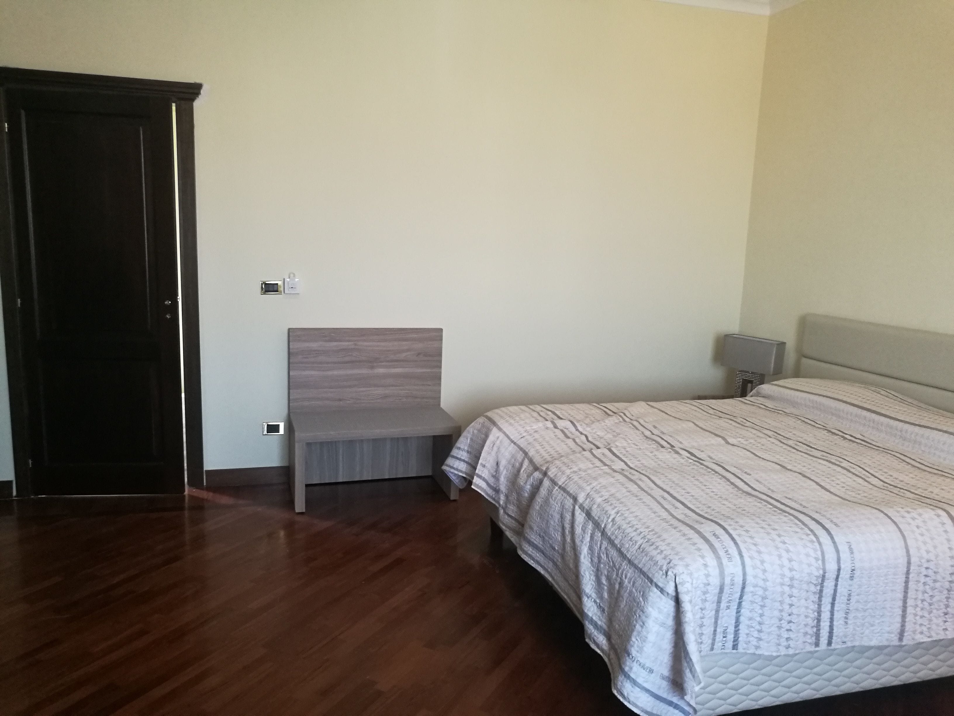 Quarto com cama, mesa de cabeceira, cadeira e guarda-roupa.