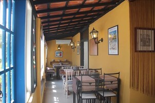 Restaurante com paredes amarelas, teto de madeira e mesas com cadeiras.