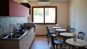 Cozinha compacta com fogão, pia e área de jantar com cadeiras e mesa.