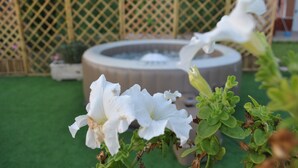 Um jardim com flores brancas e uma banheira de hidromassagem circular.