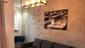 Uma sala de estar moderna com um sofá cinza, uma mesinha redonda e uma obra de arte contemporânea na parede.