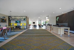 Um hall de hotel espaçoso com área de estar central, balcão de recepção e carpete estampado.