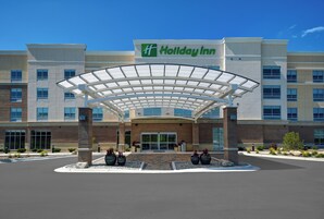 Um hotel Holiday Inn com entrada coberta, vários andares e uma entrada com paisagismo.
